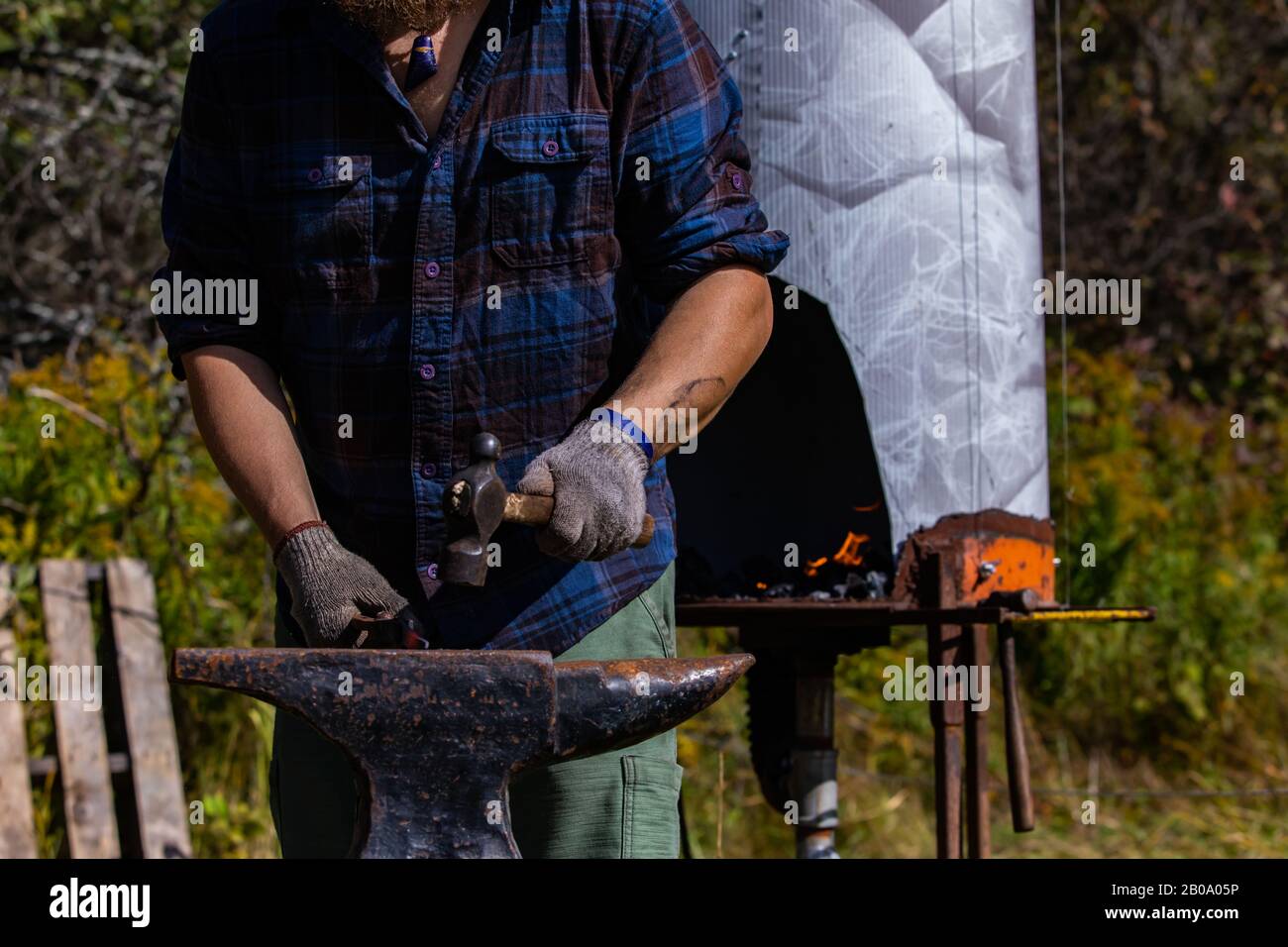A close up midsection view of a strong man at work during a blacksmith ...
