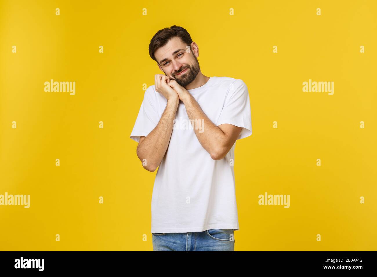Young man looks to the camera and smiles shy. He's got his hands on ...