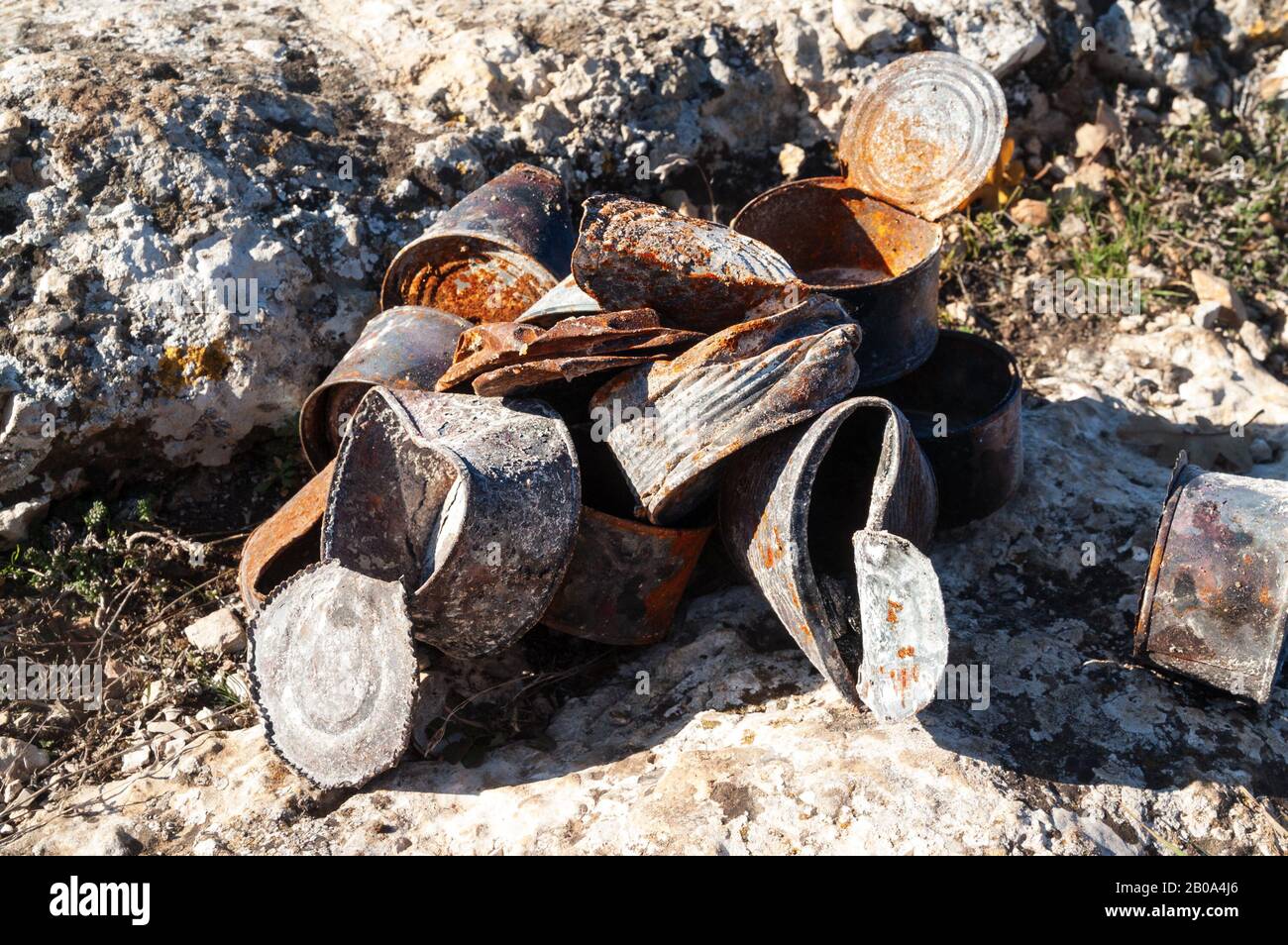 Group of old rusty tin cans covered with ash on stones at sunny day ...