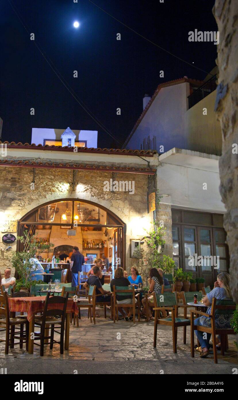 People sitting outside a taverna at night in the old fishing village of ...