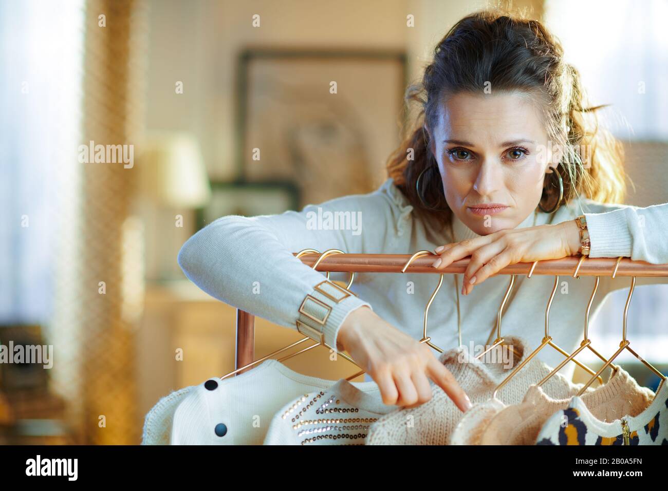 bored trendy woman in white sweater and skirt in the modern living room ...