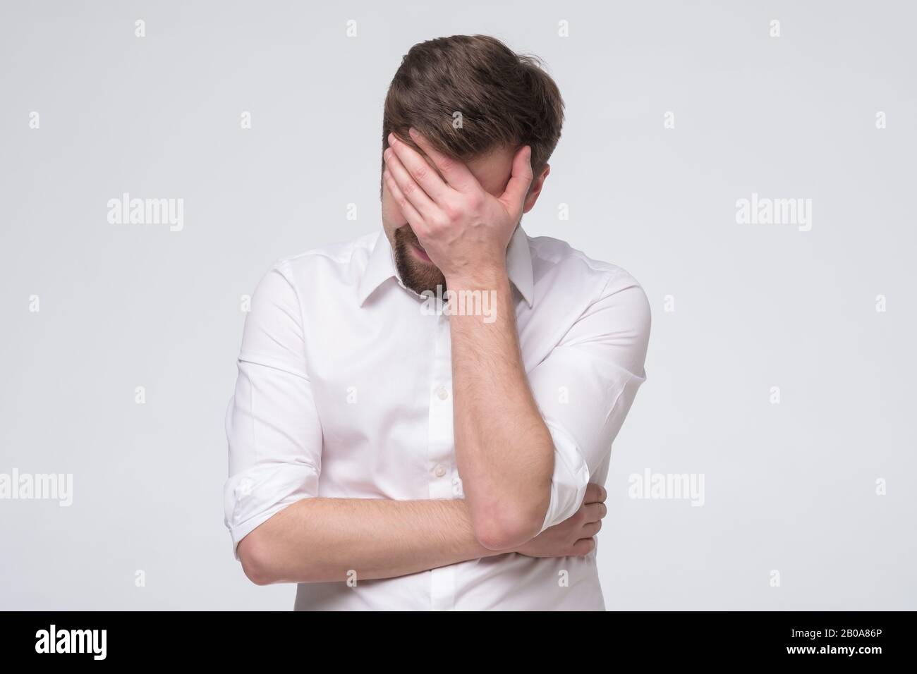 Facepalm. Disappointed man covering his face with his hand on white ...