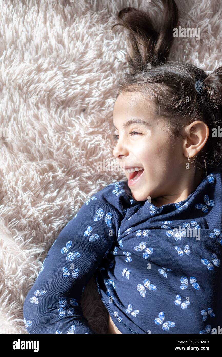 Middle Eastern young cute girl lies on a light bed in the light of ...