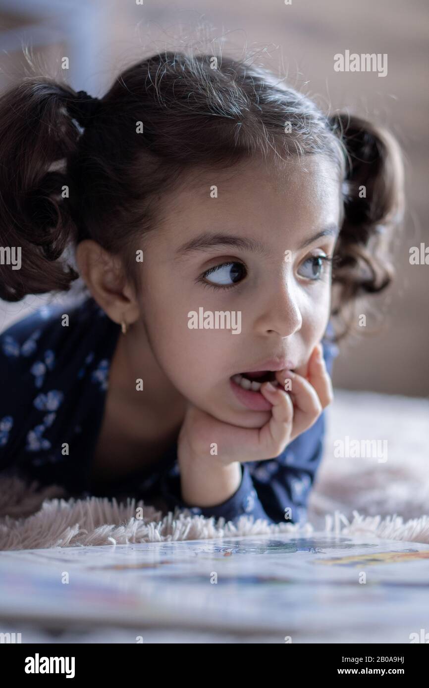 Middle Eastern young cute girl lies on a light bed in the light of ...