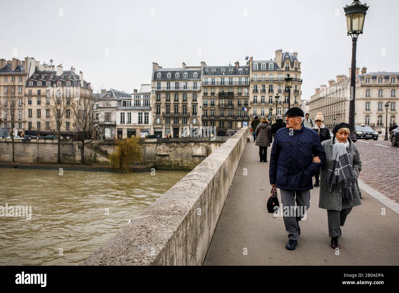 A French couple walks across a bridge over the Seine in Paris, France ...