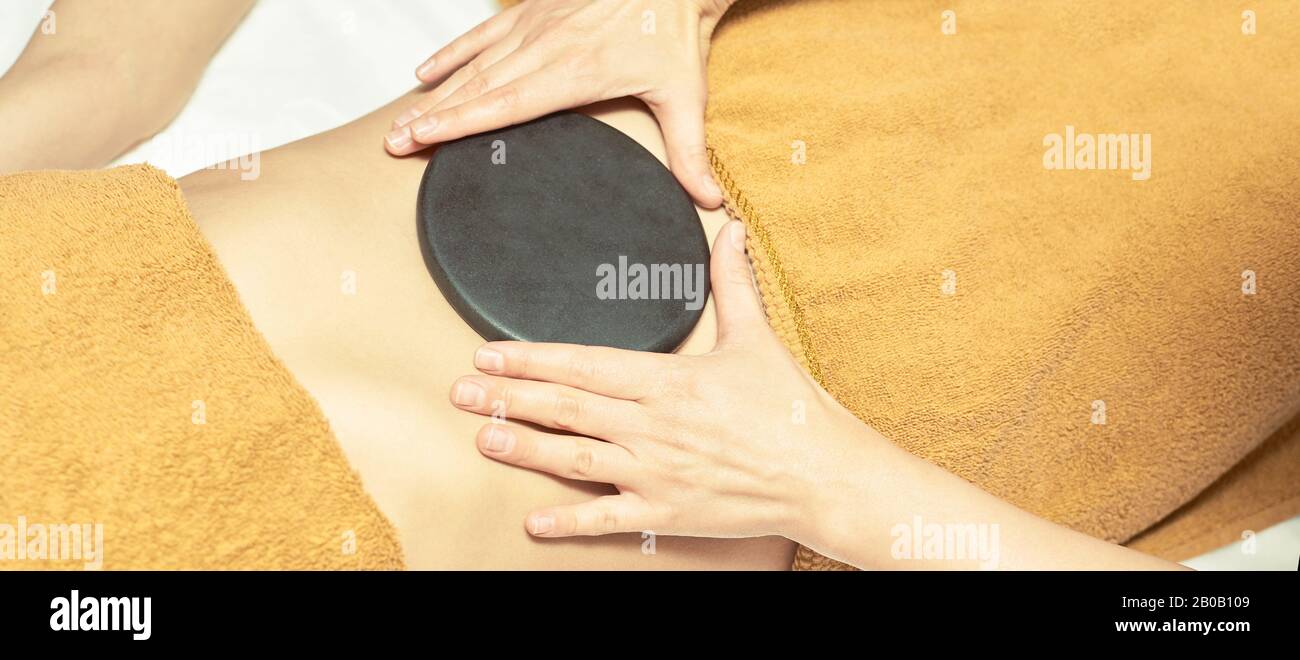 body stone massage. Hot rock masseur. Girl at salon with doctor hands ...
