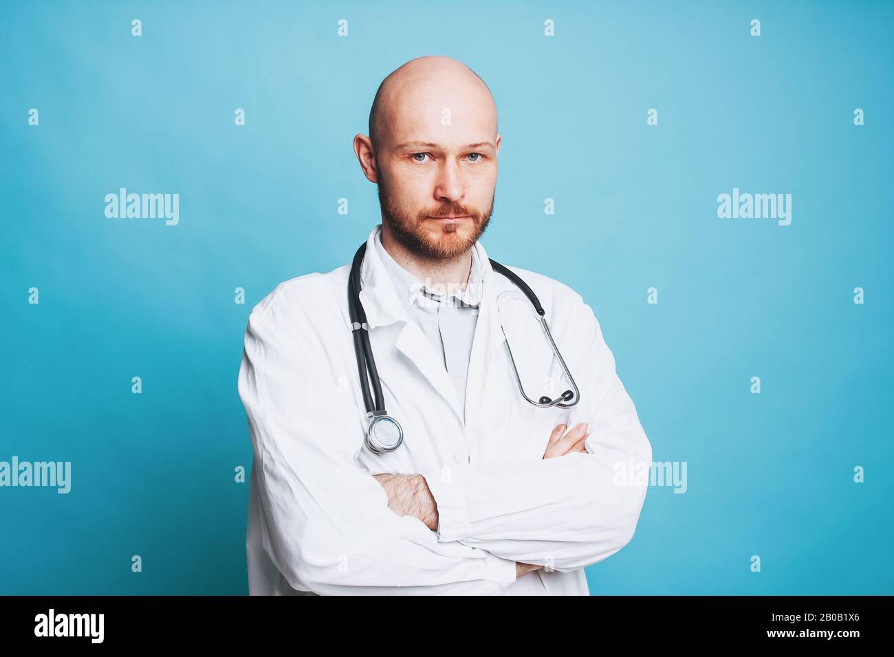 Attractive serious man bald bearded doctor looking at camera isolated ...
