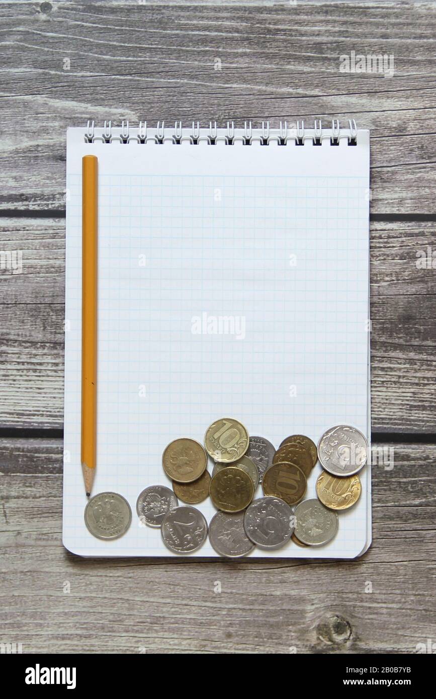 Notepad with a blank white sheet in a checker paper with russian coins ...