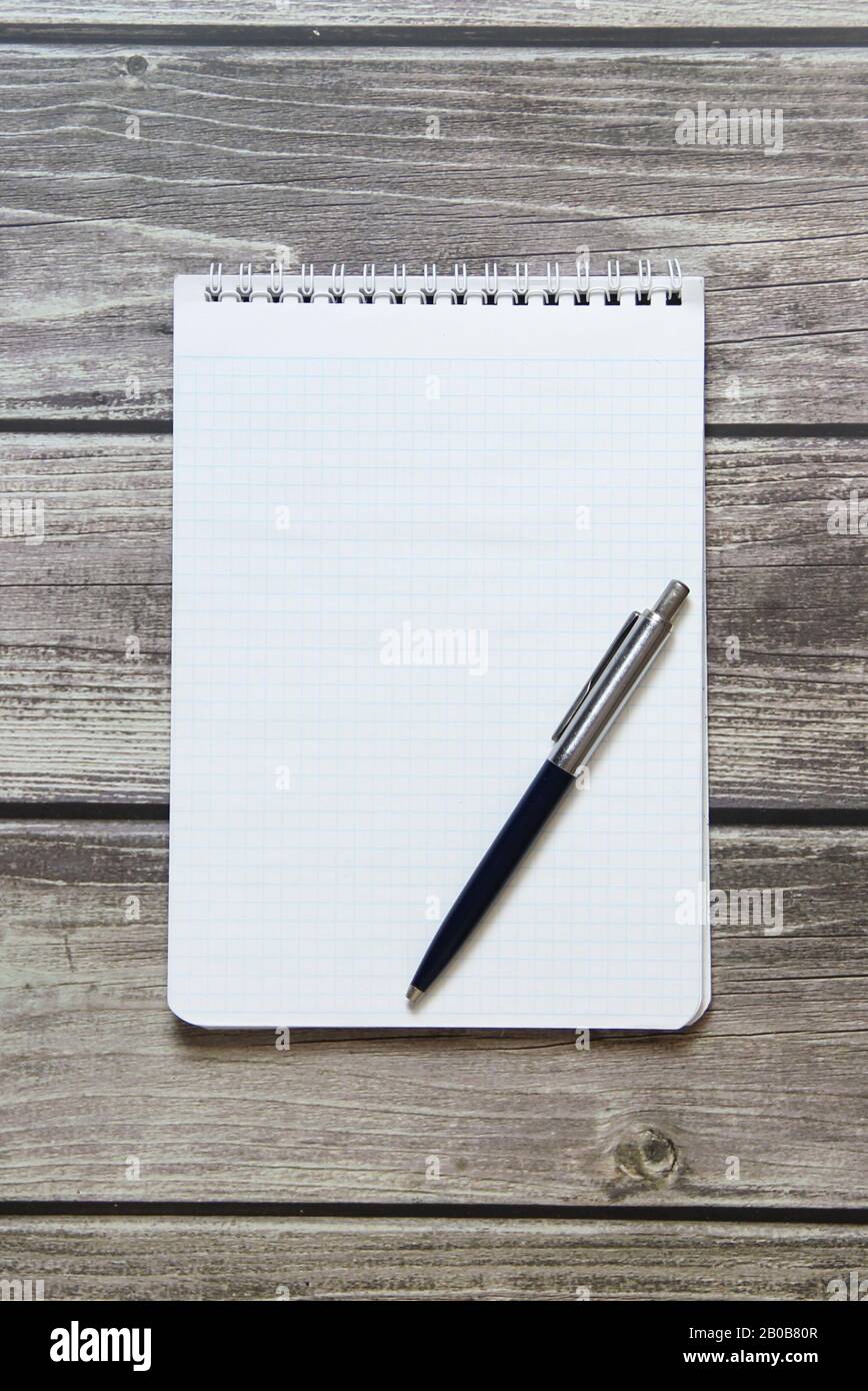 Notepad with a blank white sheet in a checker paper with ball pen lies ...