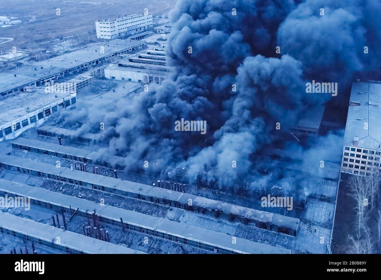 A major fire at the factory. dark puffs of smoke from buildings Stock ...
