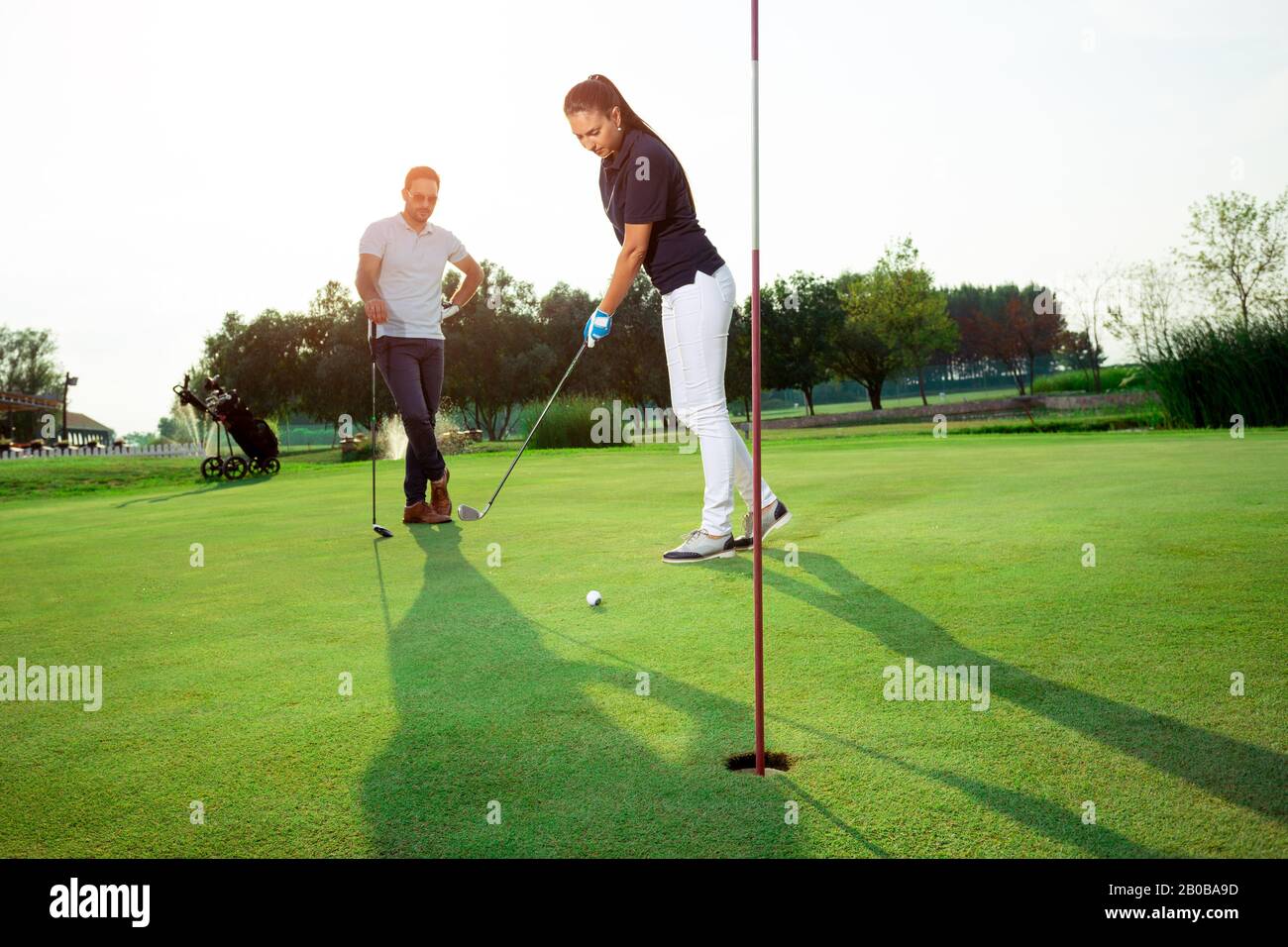 Beautiful young woman is getting ready to hit a golf ball Stock Photo ...