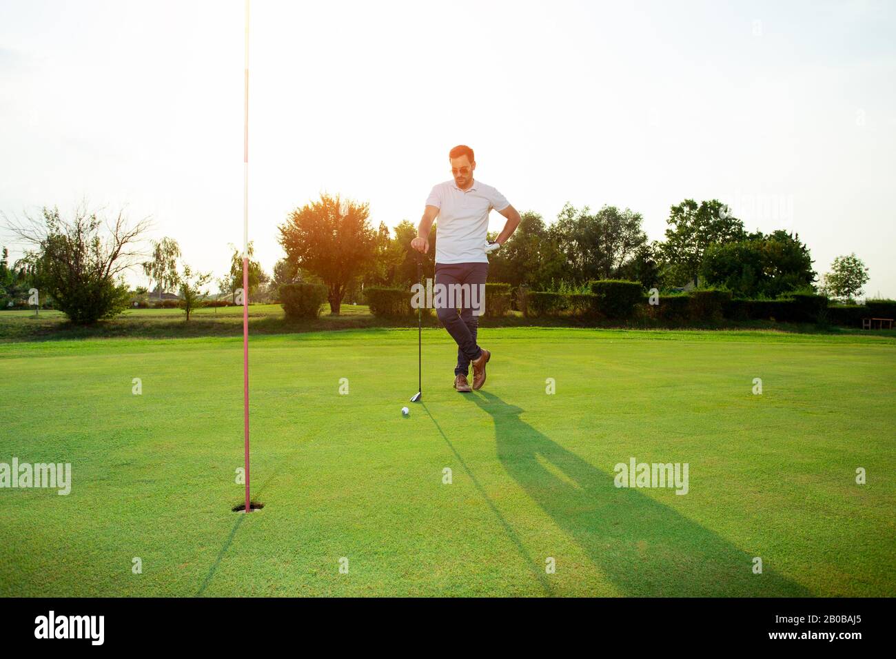 An attractive male golfer is standing on a golf course during the ...