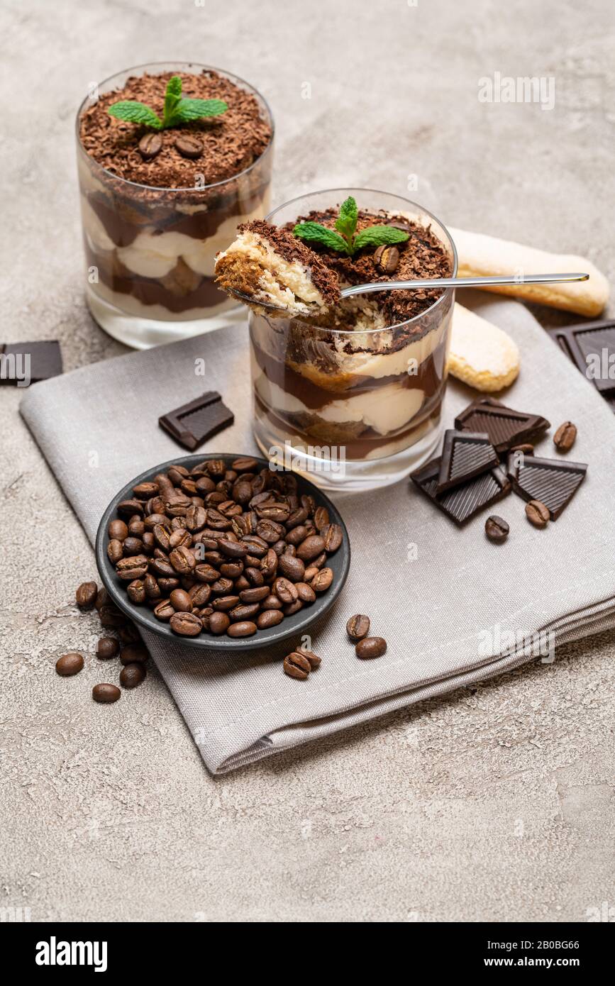 Classic Tiramisu Dessert In A Glass Cup Pieces Of Chocolate And Savoiardi Cookies On Concrete