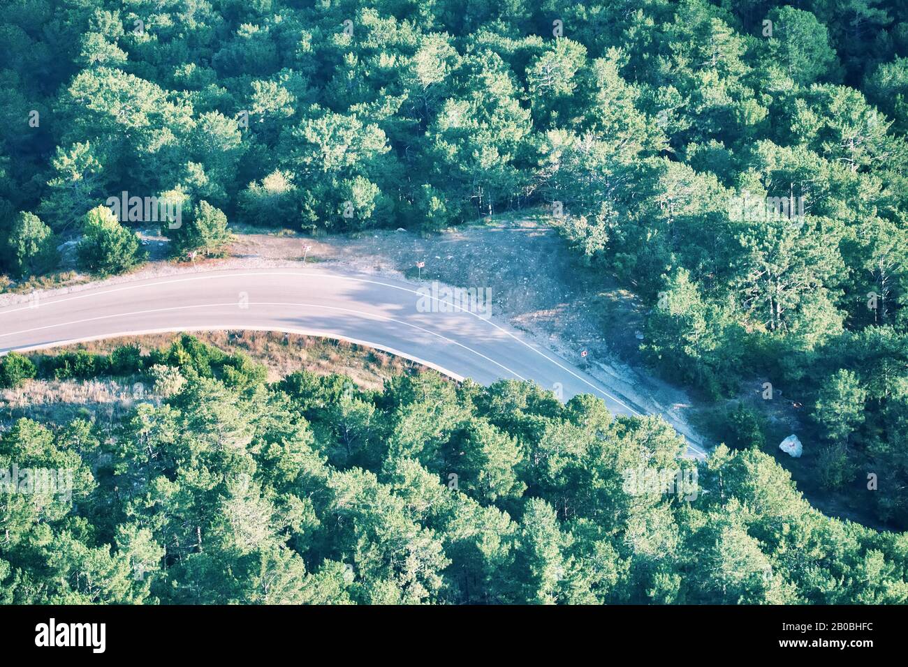 Mountain road aerial view. Asphalt highway on a green forest slope ...