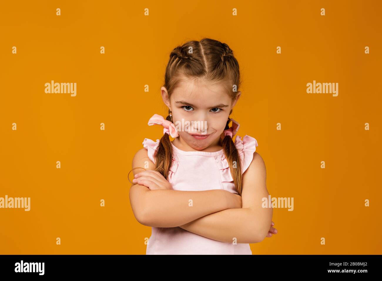 offended sad little child girl in dress on yellow background. Human ...