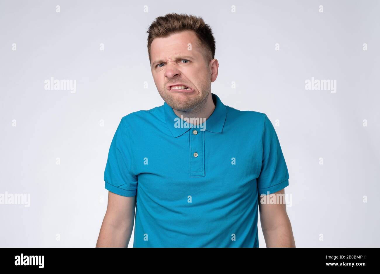 Young angry man is about to lose his temper on gray background ...