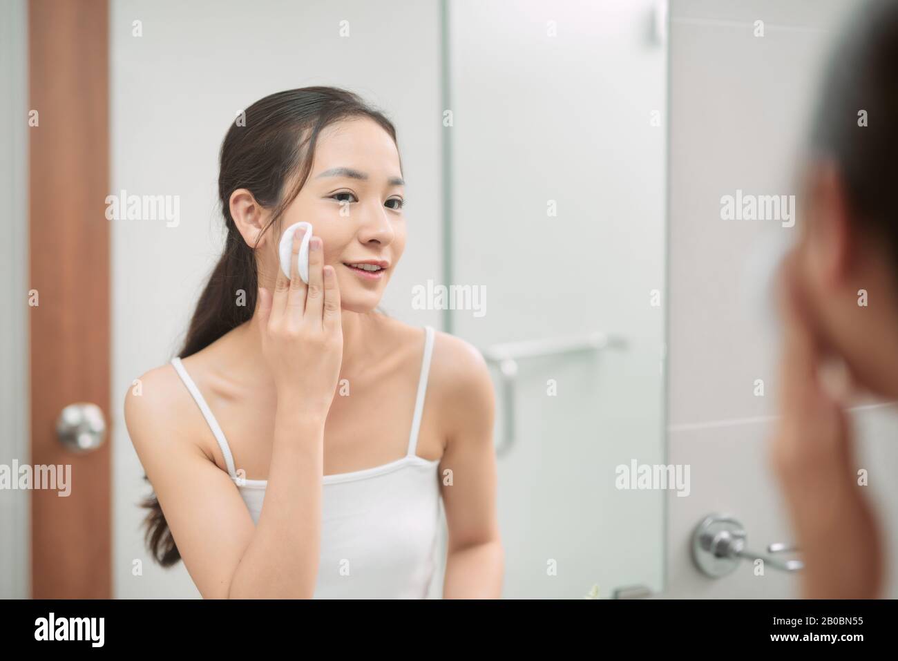 Healthy fresh girl removing make up from her face with cotton pad ...