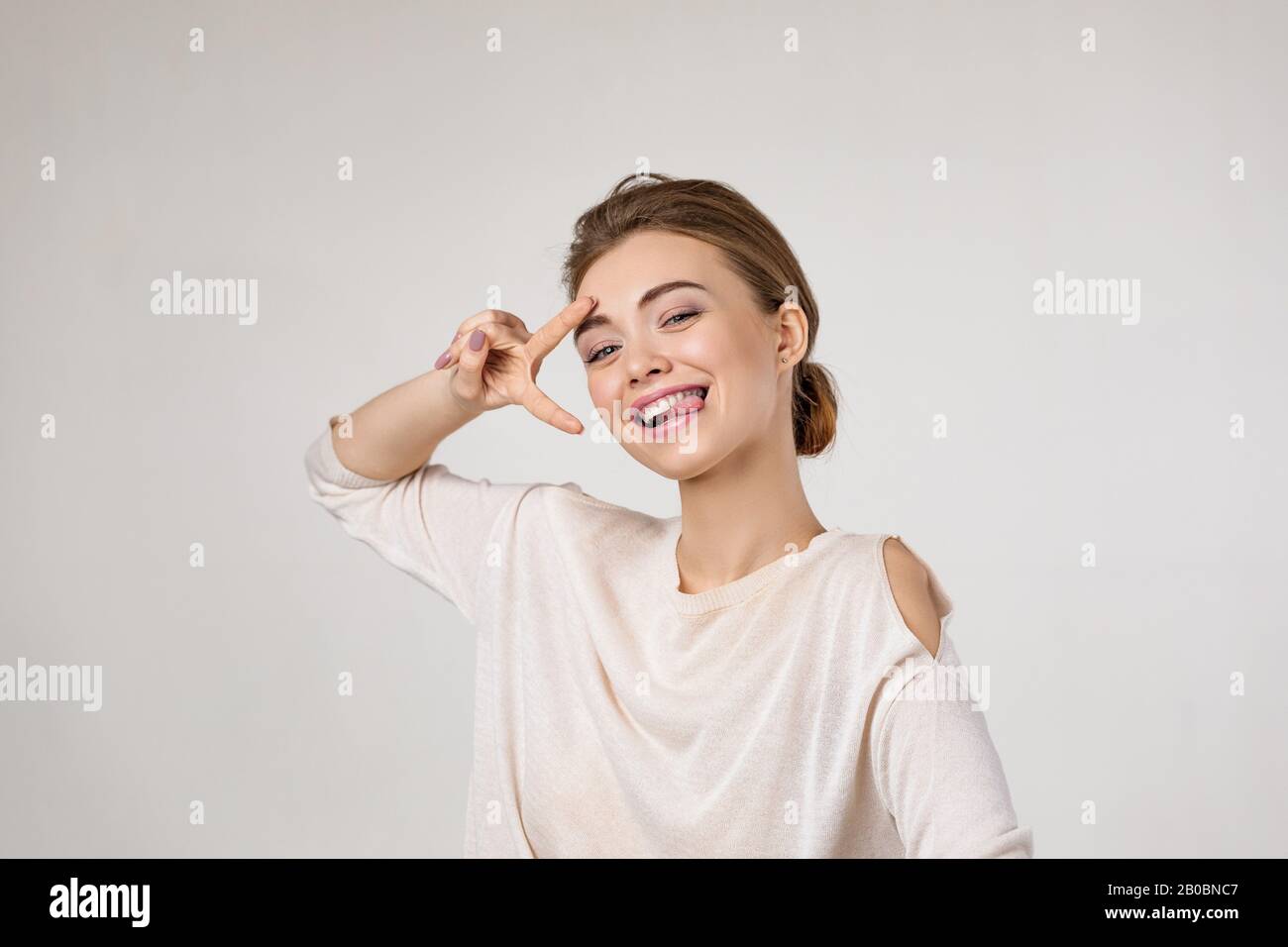 smiling young woman showing victory sign and looking at camera. Human ...