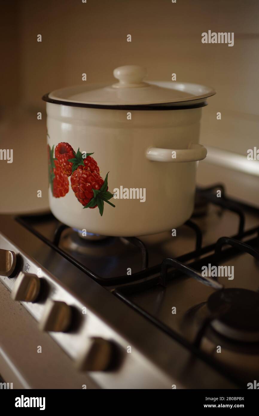 Enamel pan with a slightly open lid during cooking on a gas stove Stock ...