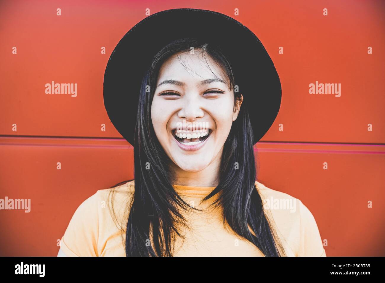 Portrait of happy asian girl smiling with coral background - Young ...