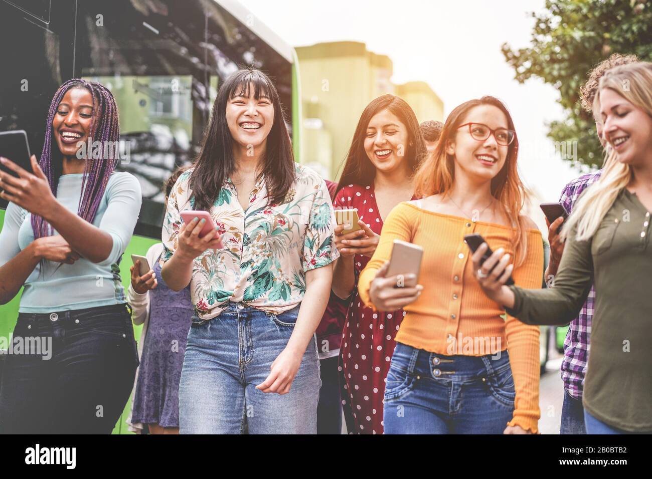 Happy friends using smartphones at bus station - Young students people ...