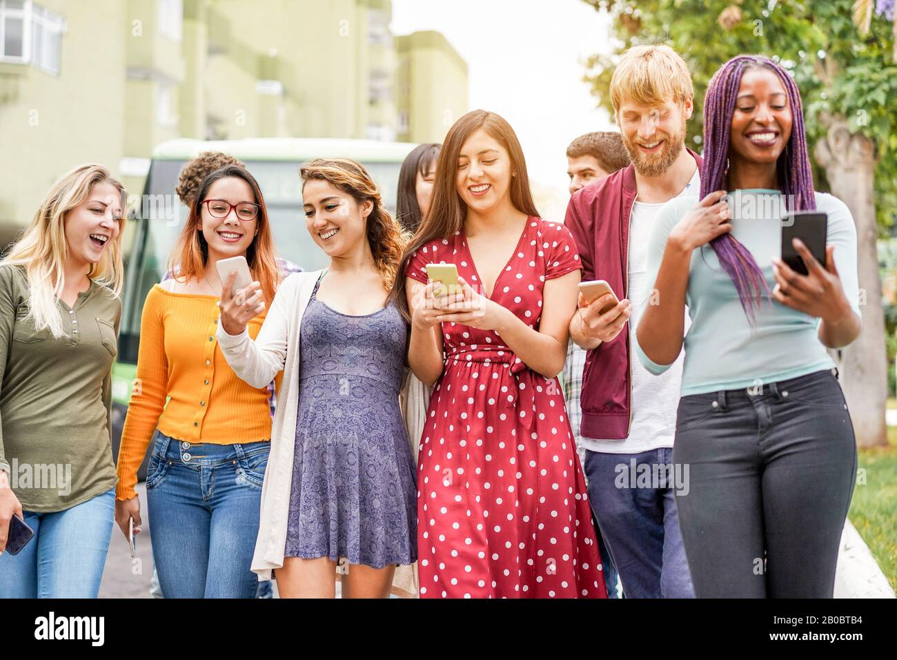 Happy millennial friends using smartphones at bus station - Young ...