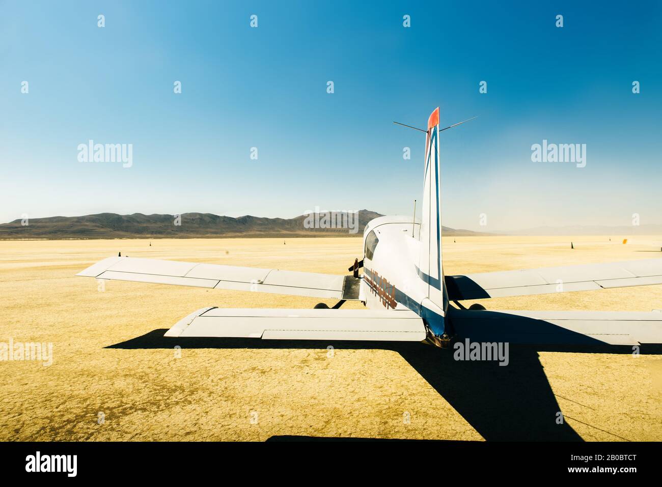Small airplane in the desert with a blue sky and the sert all around ...