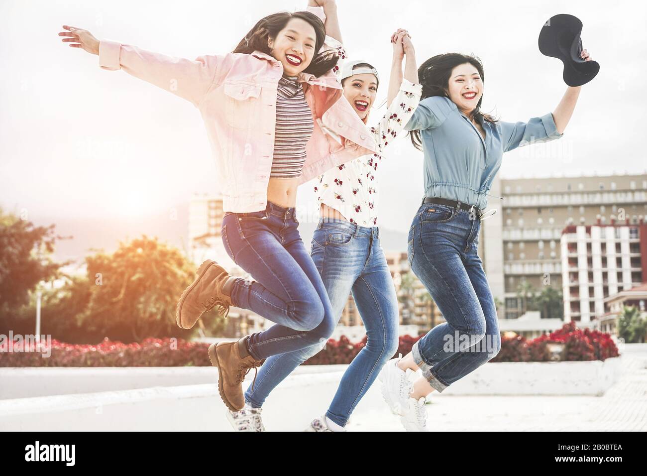 Millennial asian women jumping outdoor - Happy girls friends having fun ...