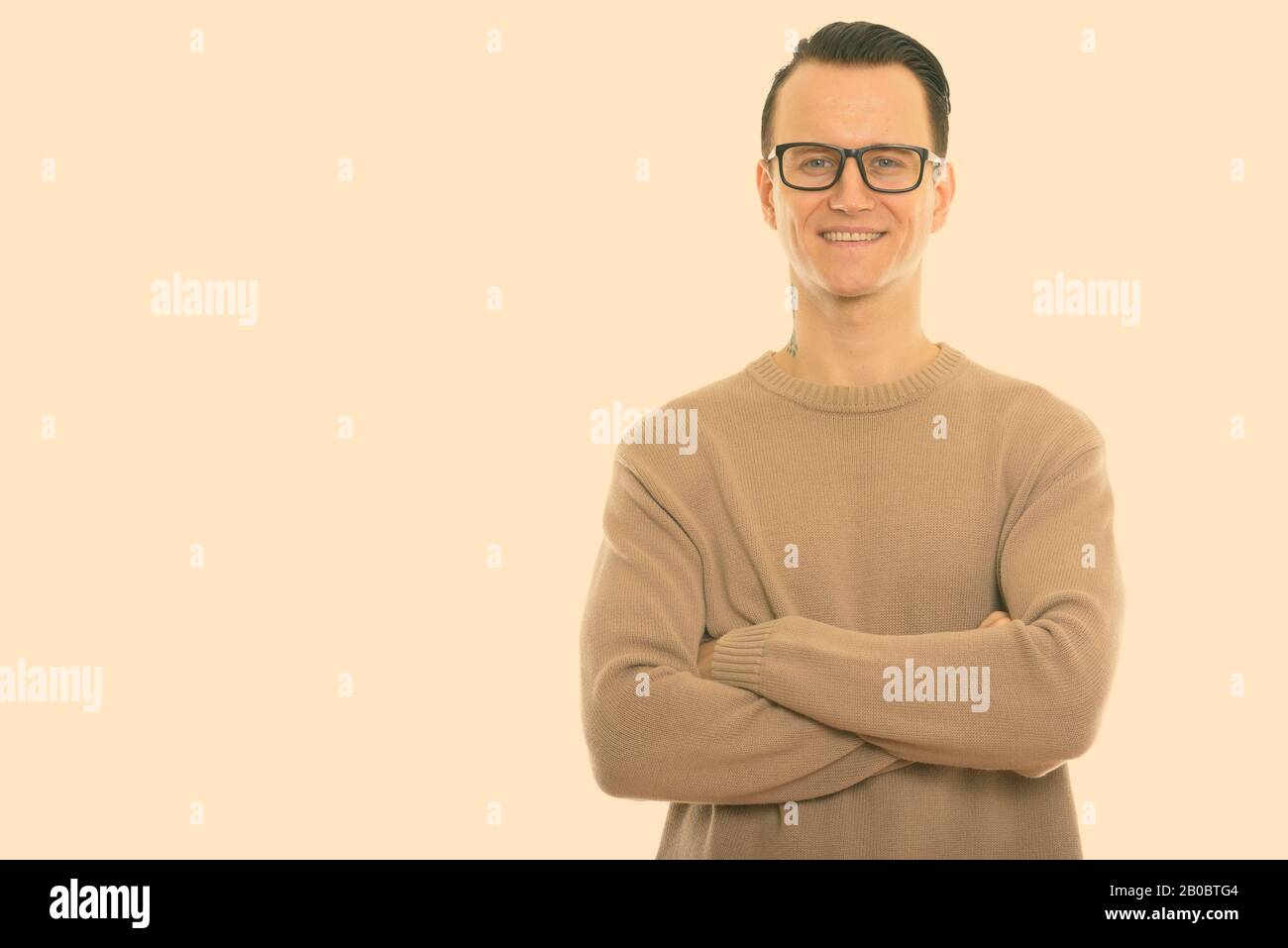 Studio shot of young happy man smiling while wearing eyeglasses with ...