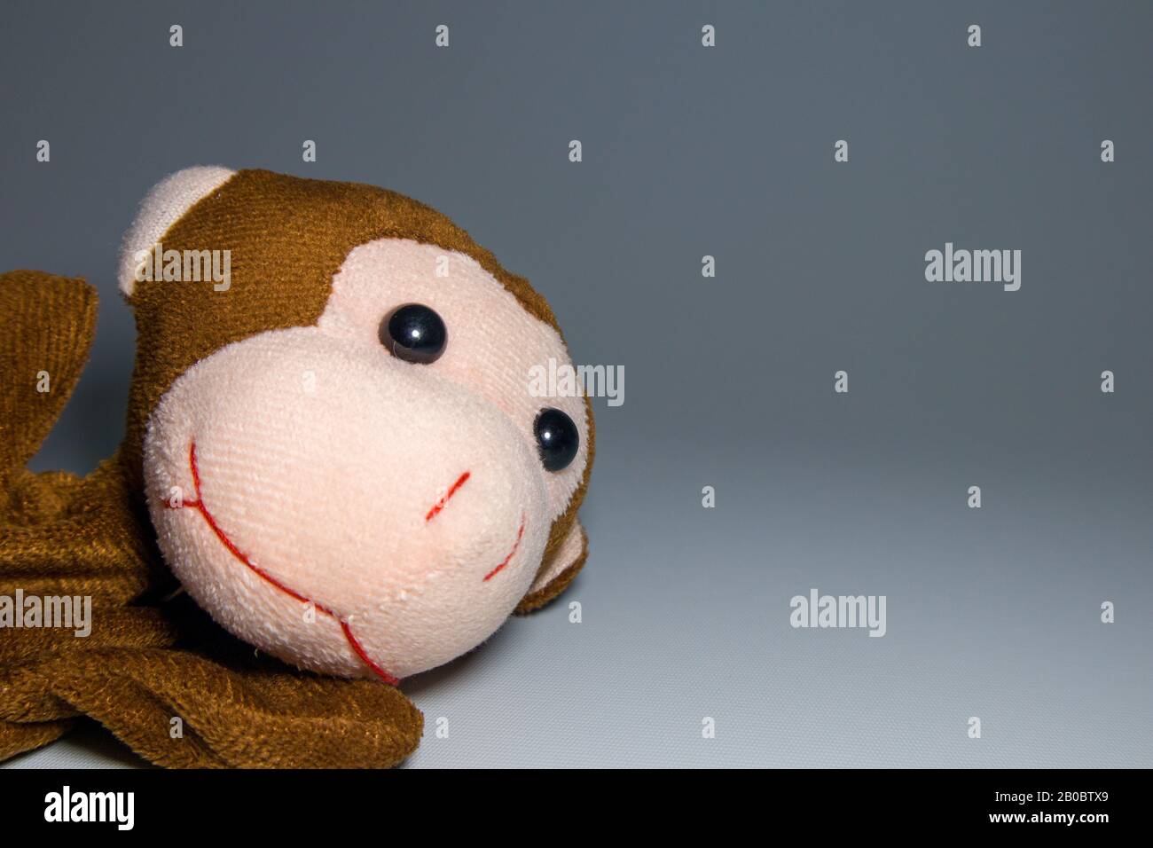 A brown monkey toy on a grey background Stock Photo - Alamy