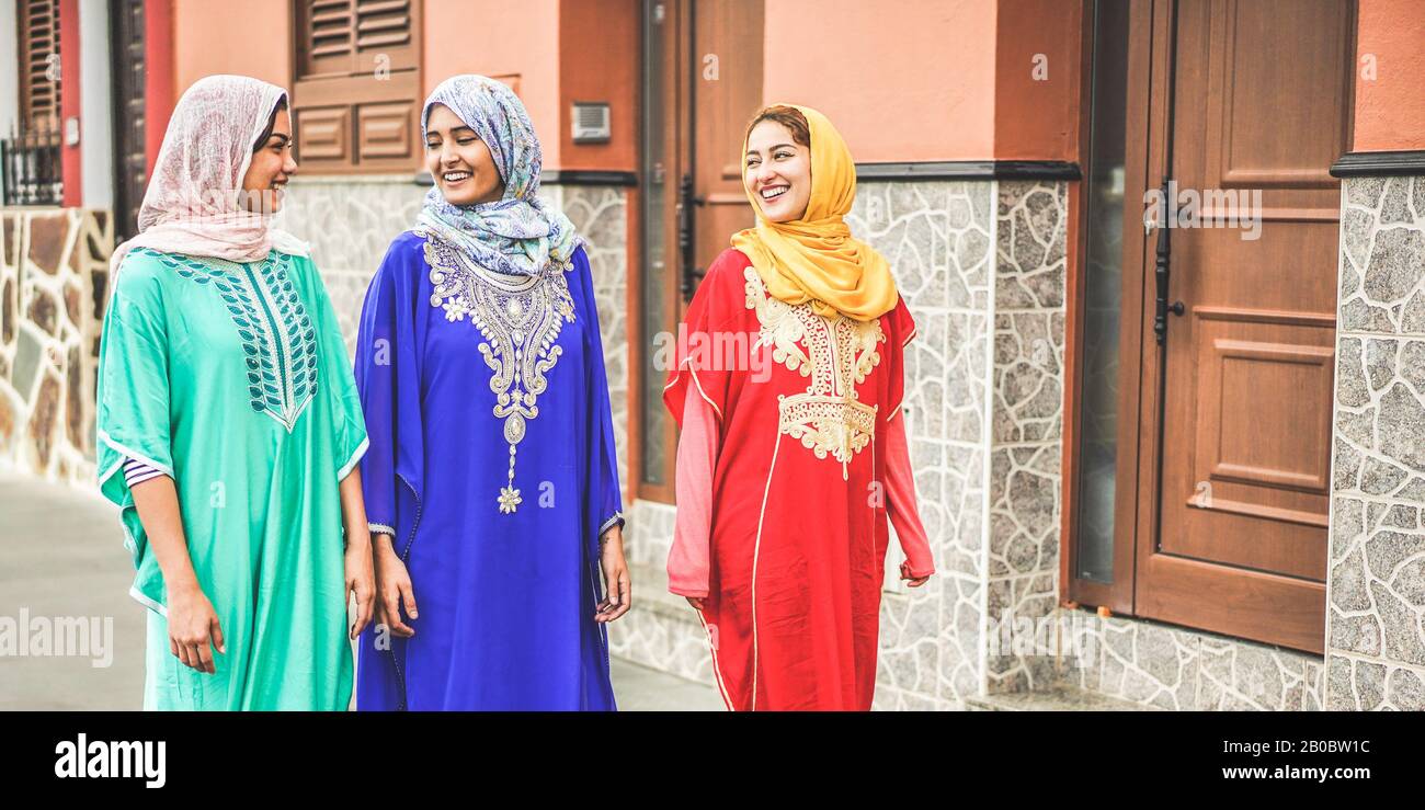 Happy arabic friends walking in city center with traditional islamic ...