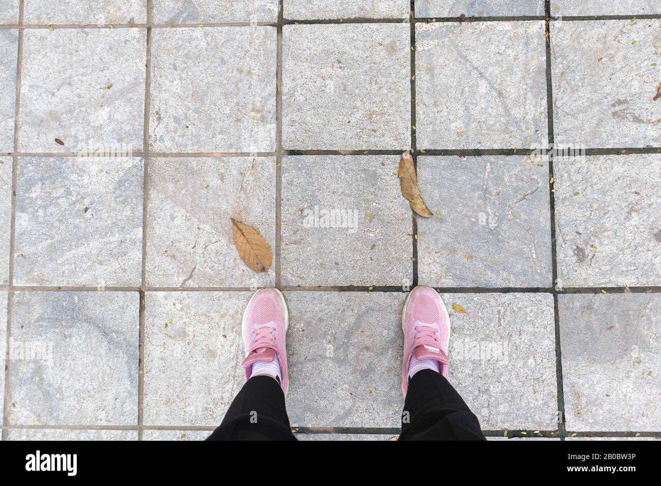 Pink snickers with legs on a grey street with two leaf Stock Photo - Alamy