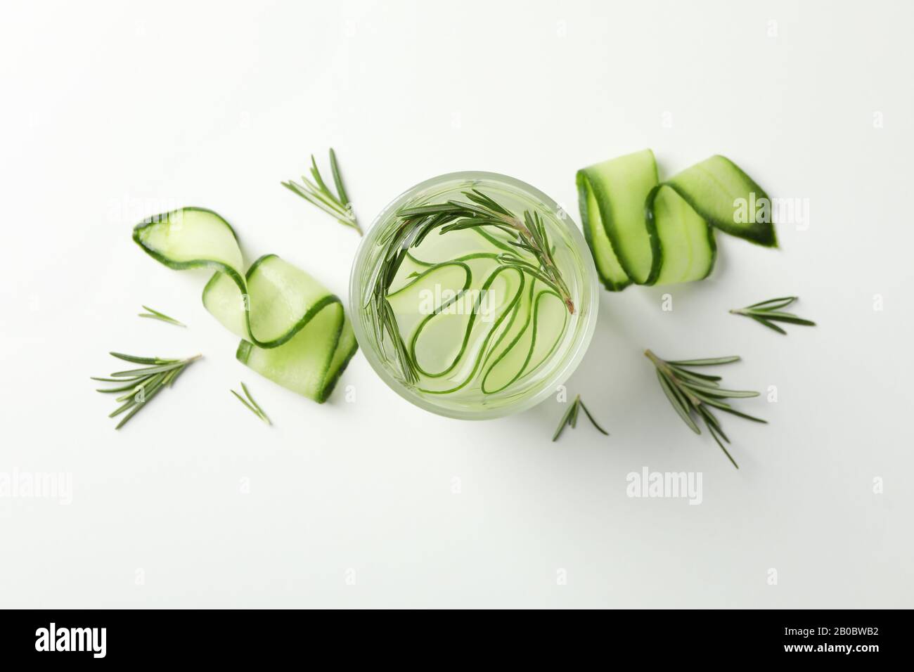Glass with cucumber water and slices on white background, top view ...