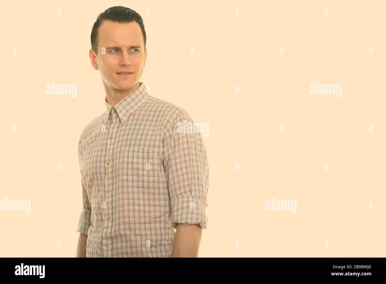Studio shot of young handsome man thinking while looking back Stock ...