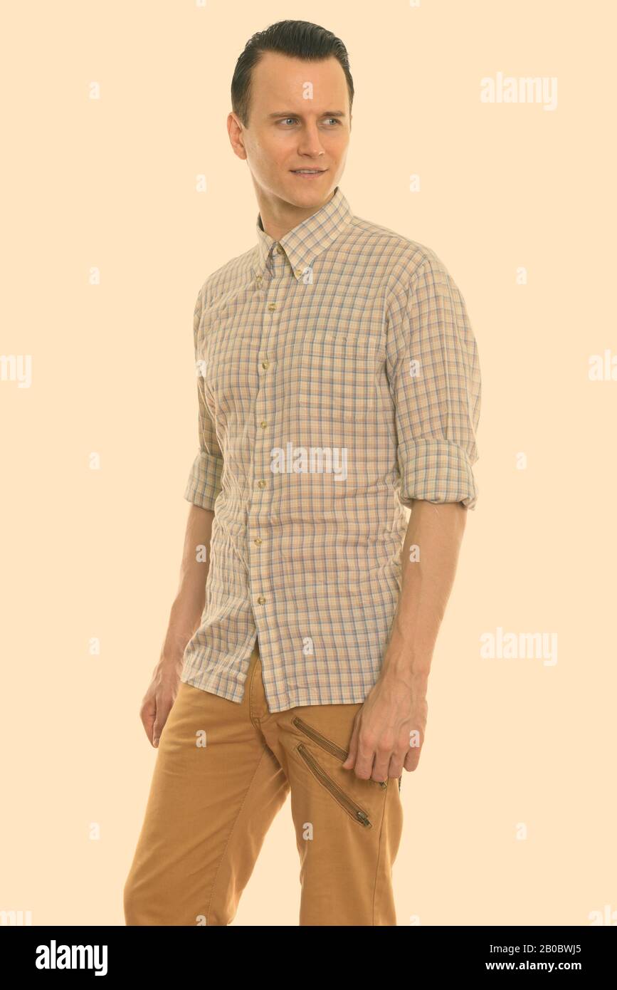 Studio shot of young handsome man standing and thinking while looking ...