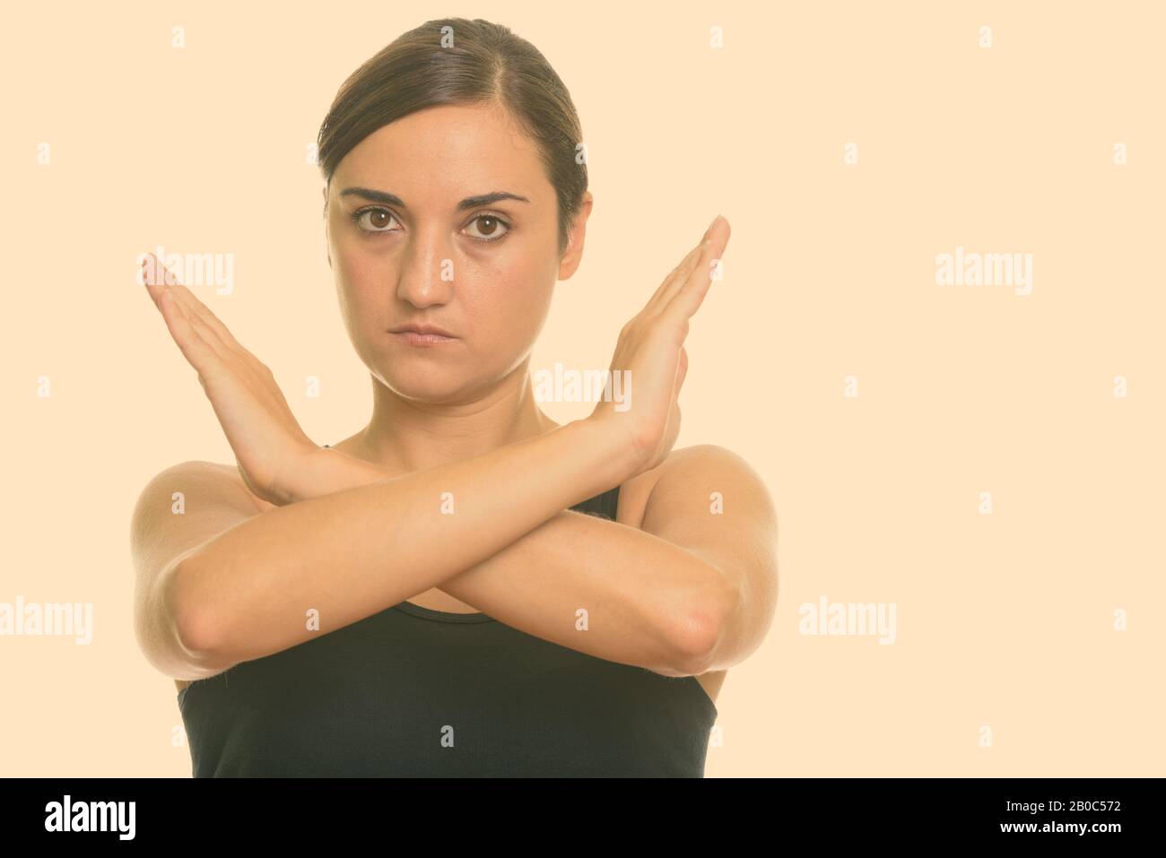 Studio shot of beautiful woman showing stop sign with both hands ...