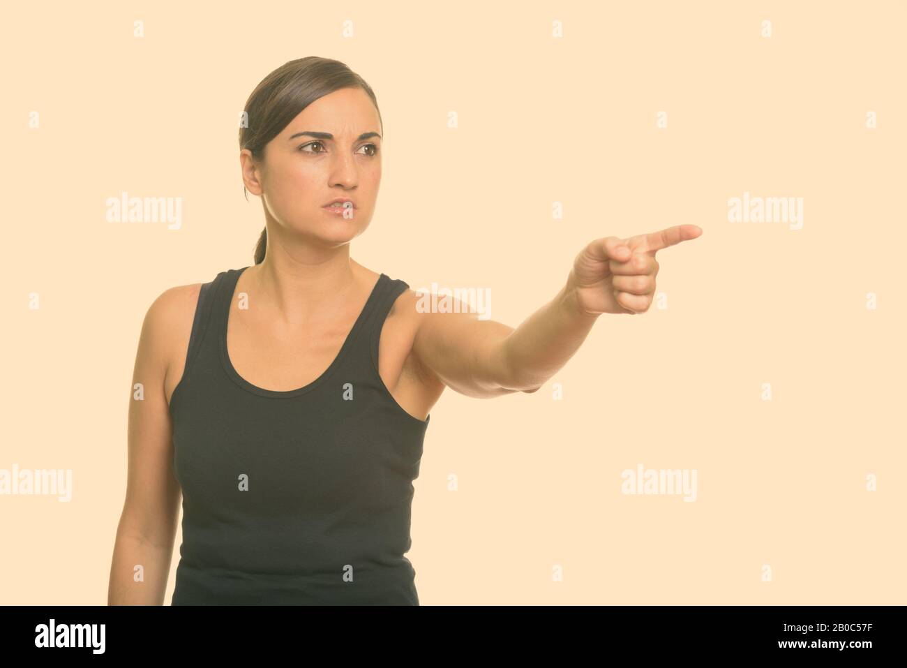 Studio shot of beautiful woman looking angry while pointing finger at ...