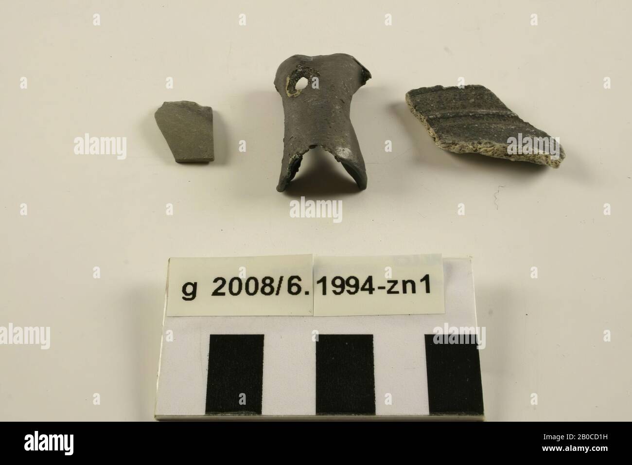 1 rounded piece of lead with a hole in it and 2 shards of earthenware ...