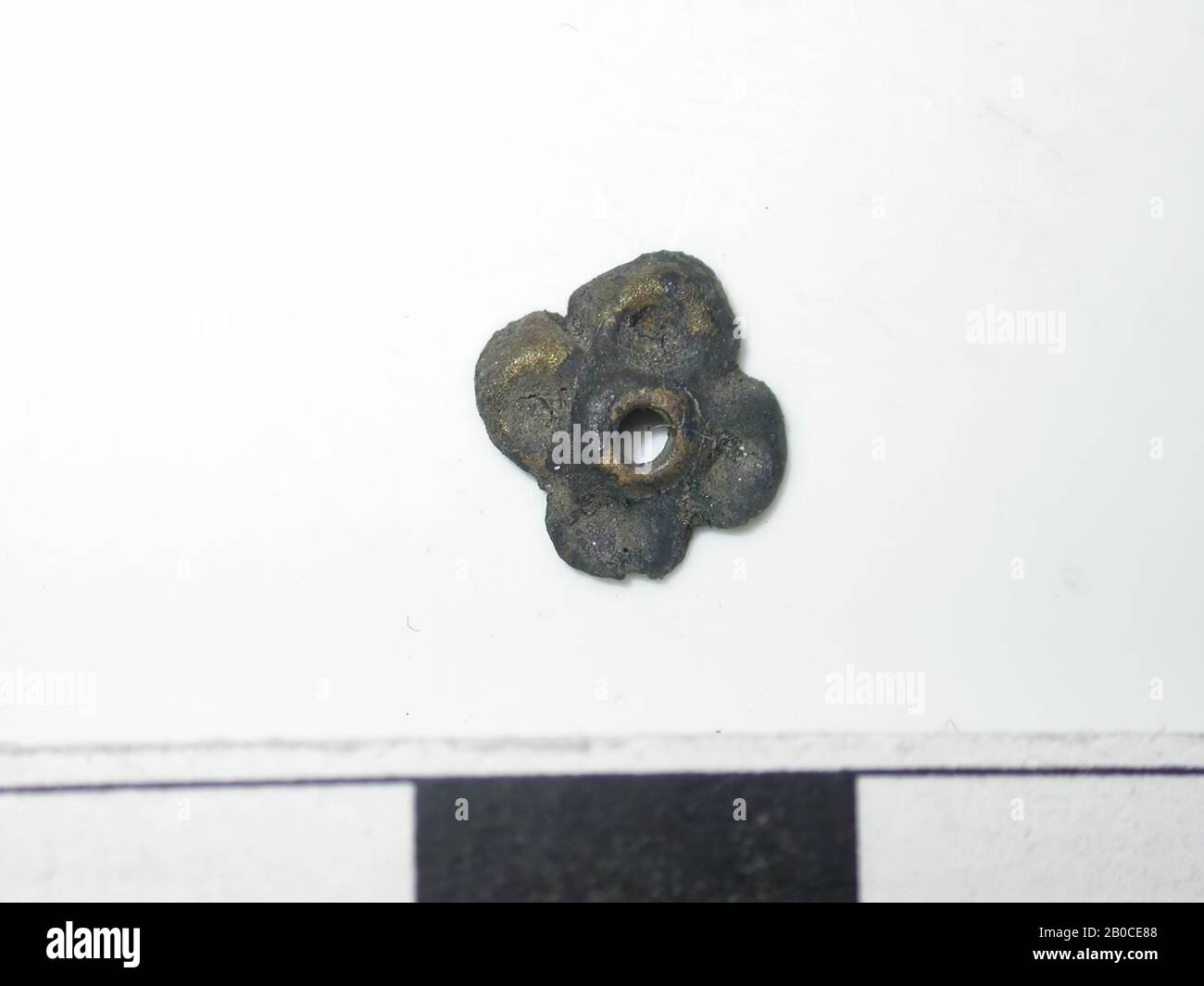 4-lobed figure, gold-colored with dark spots (copper alloy). 4-lobed ...
