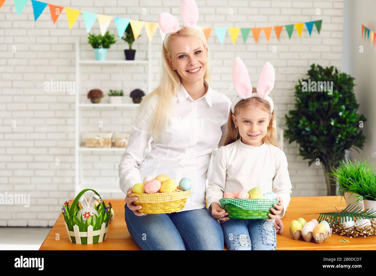 Happy easter. Daughter and mother with rabbit ears decorate Easter eggs ...