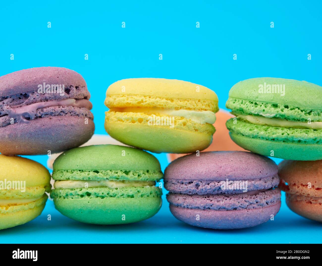 multi-colored round baked macarons cakes on a light blue background ...
