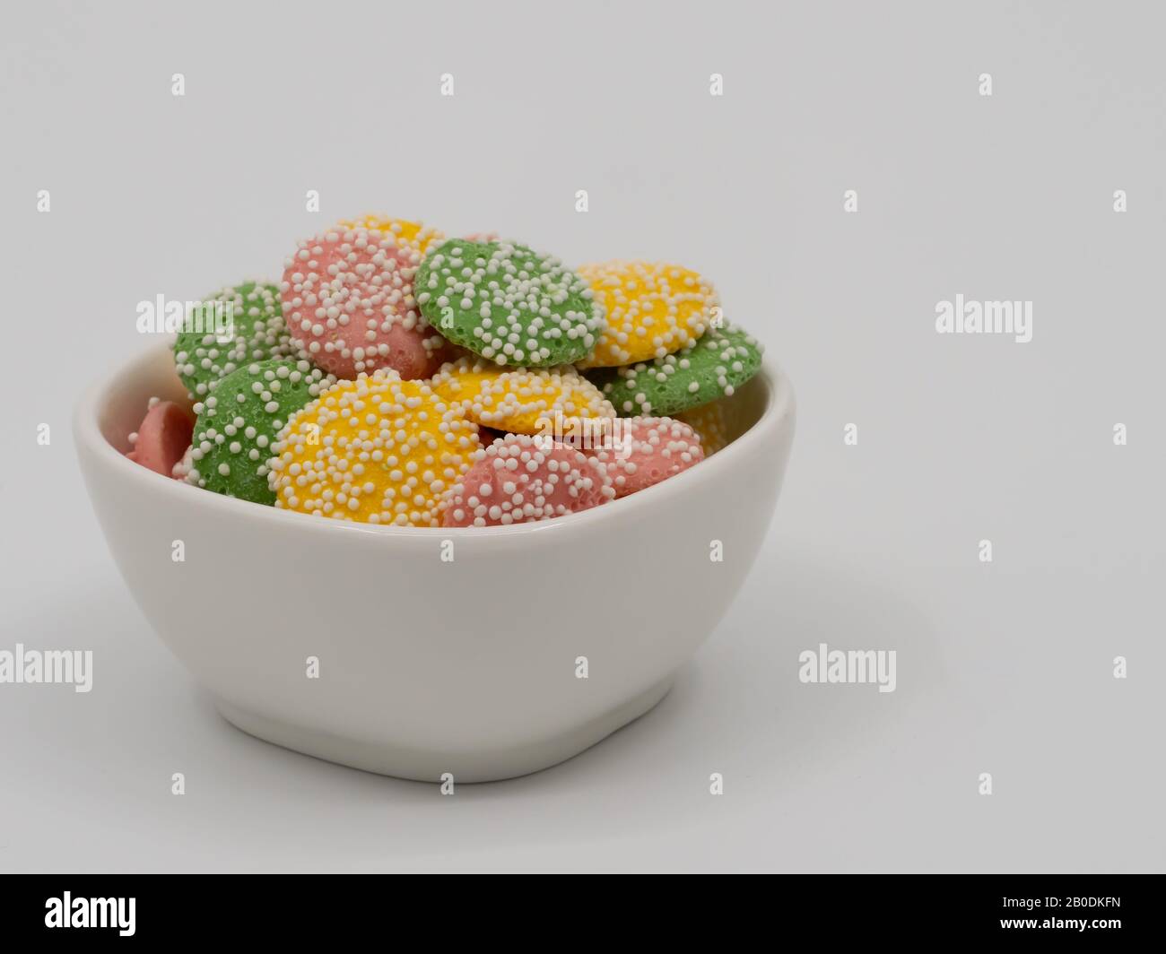 White bowl filled with candy, little pastel colored white chocolate ...