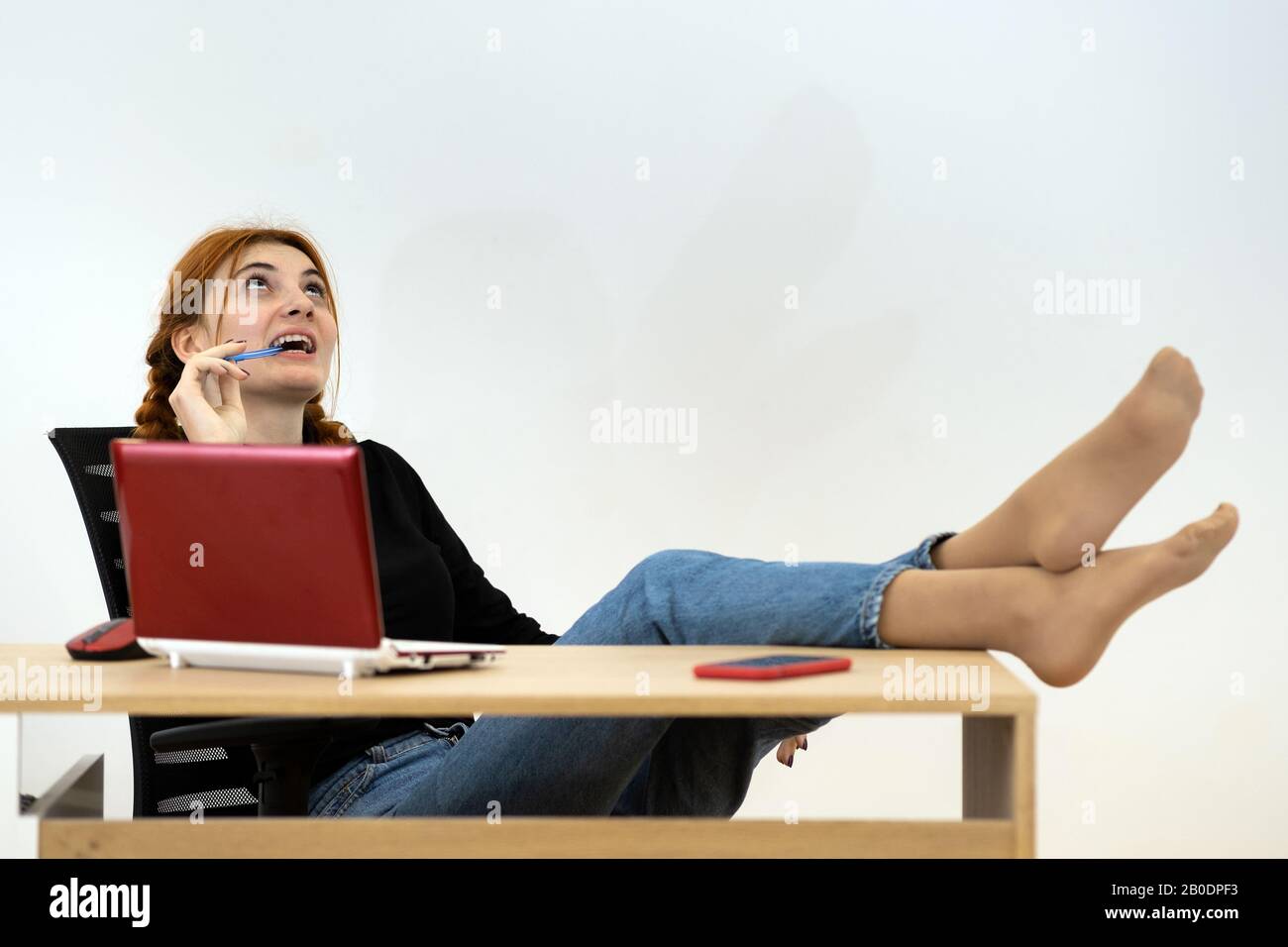 Happy young office worker woman sitting relaxed with feet on table ...