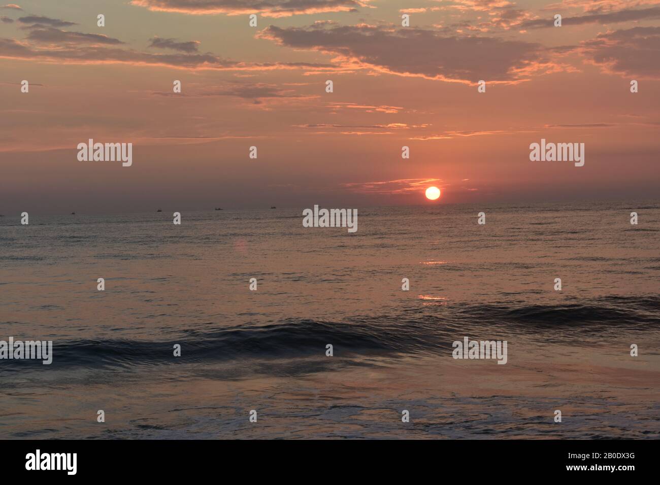 sun setting in a ocean with small waves and beautiful sky Stock Photo ...