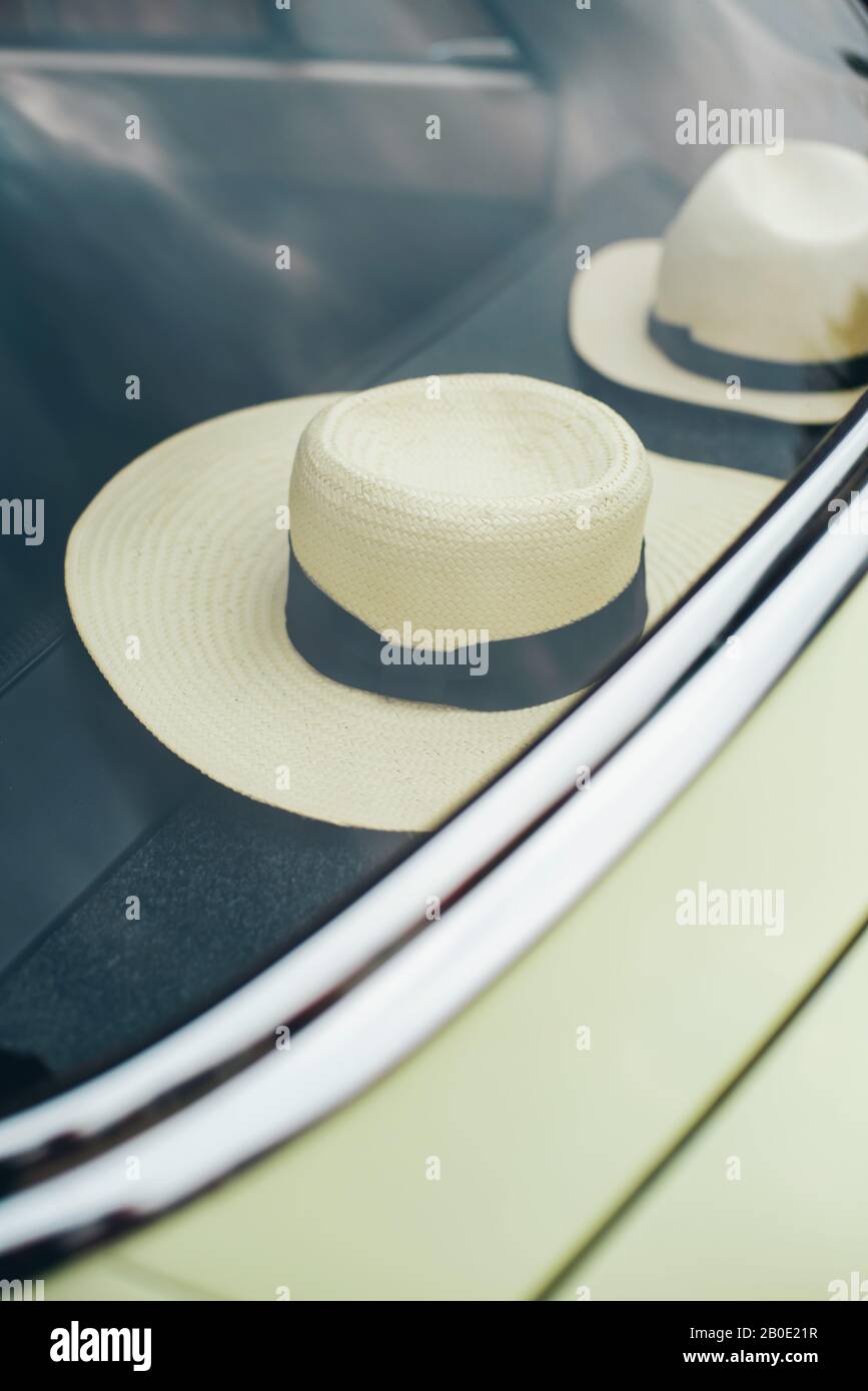 Two straw hats on back seat of vintage car. View through rear window ...