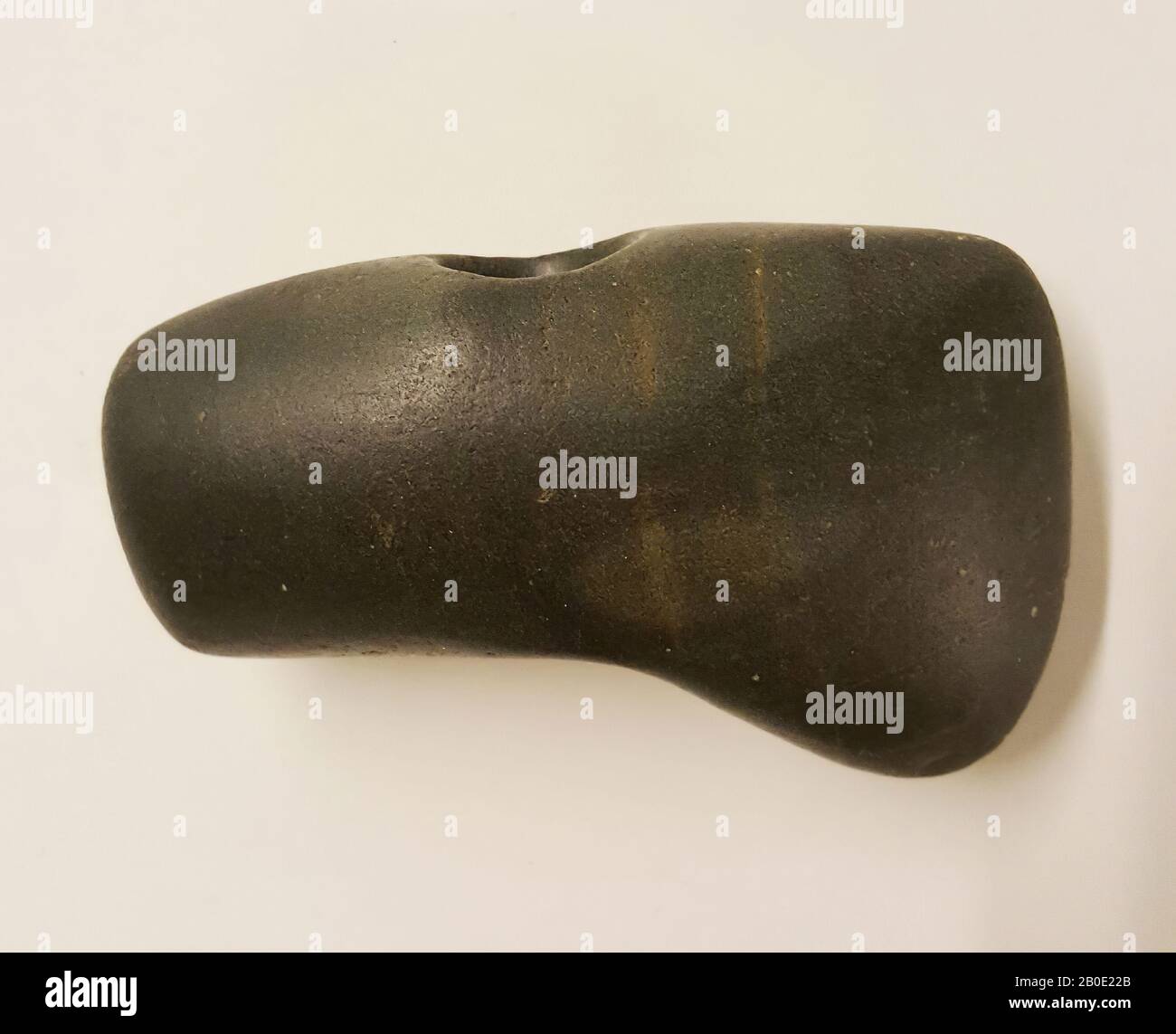 A complete green ax, polished, slightly vonvex with perforation. Top is ...