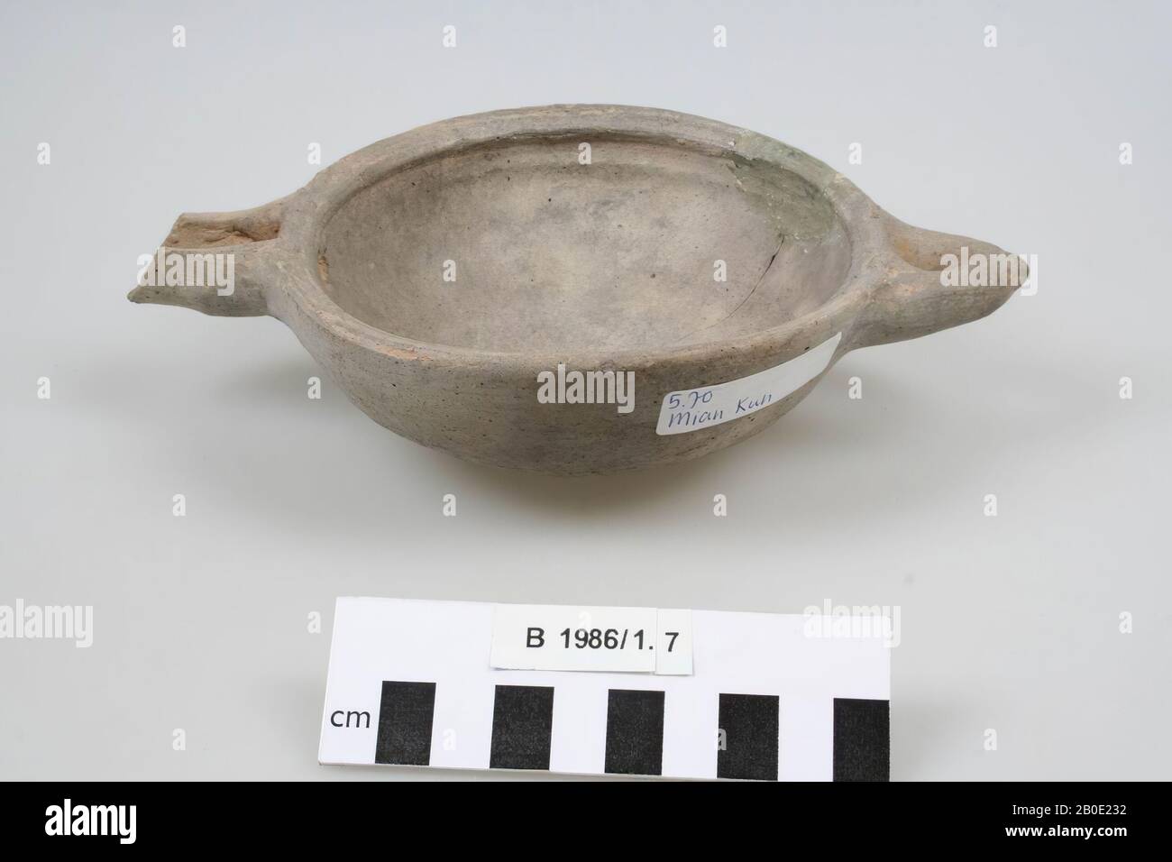 A gray dish with a triangular ear and a spout. A piece of edge is ...