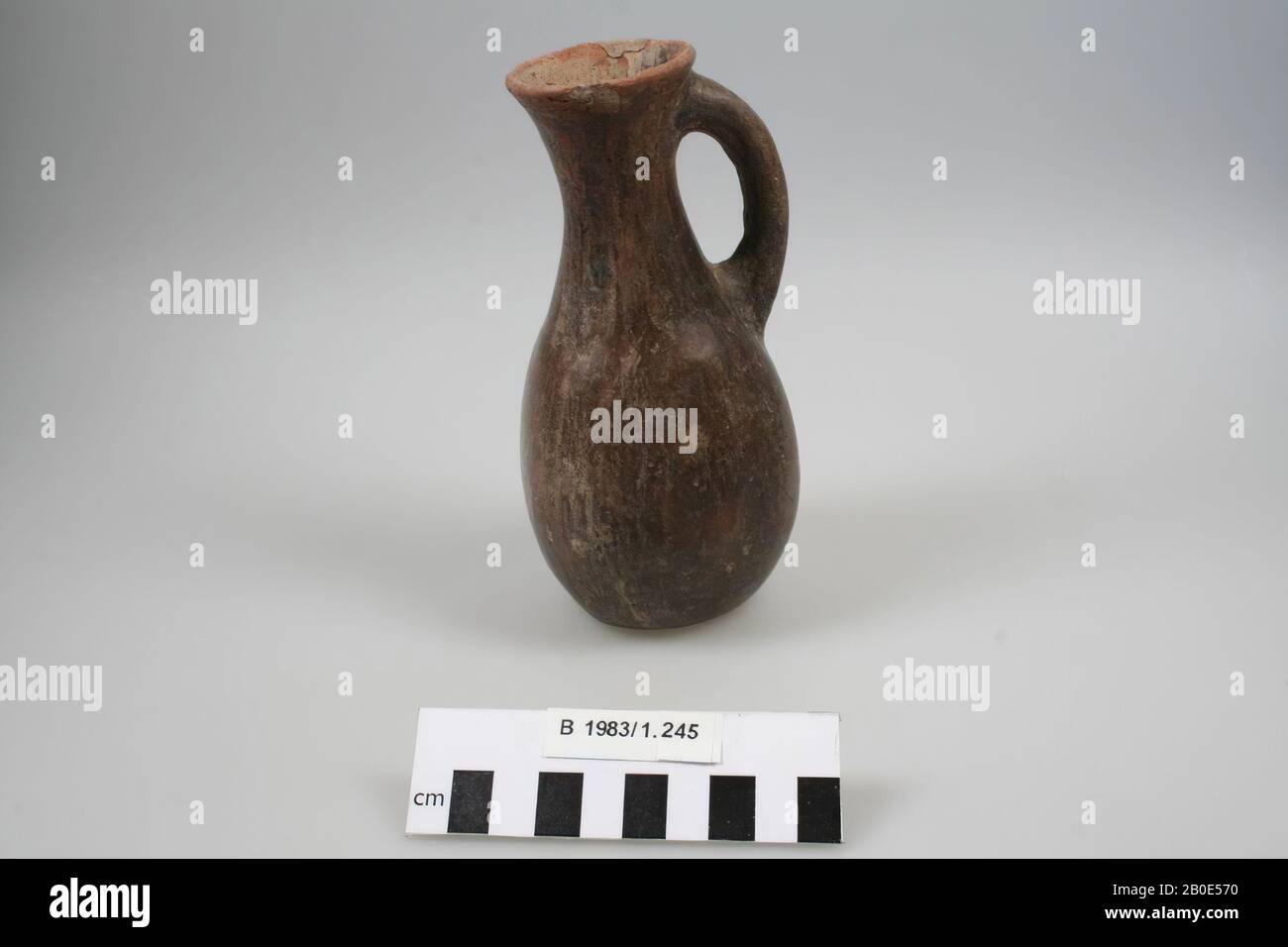 A pottery jug or jug with a stretched round body and a long funnel ...