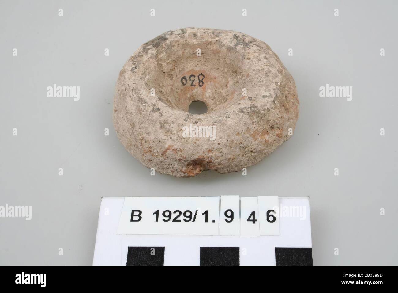 A fragment of a disk-shaped stone. The hole is hourglass-shaped ...