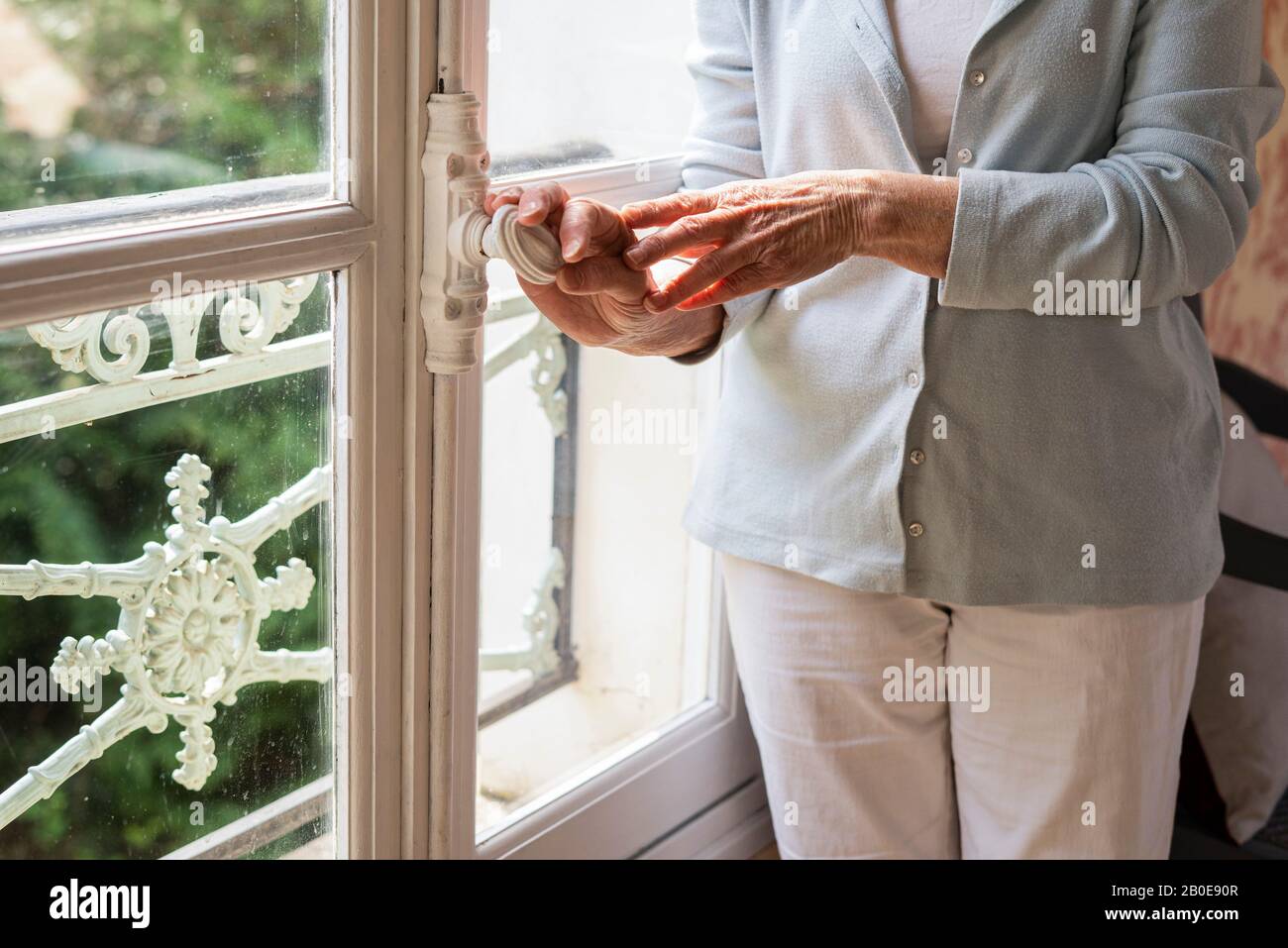 Senior woman standing near window Stock Photo - Alamy